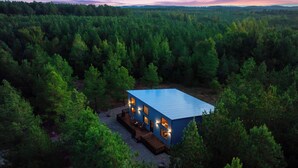 Uma cabana moderna com telhado azul, rodeada por uma floresta densa.