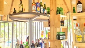 Interior de madeira com estantes repletas de garrafas de bebidas e caixas.
