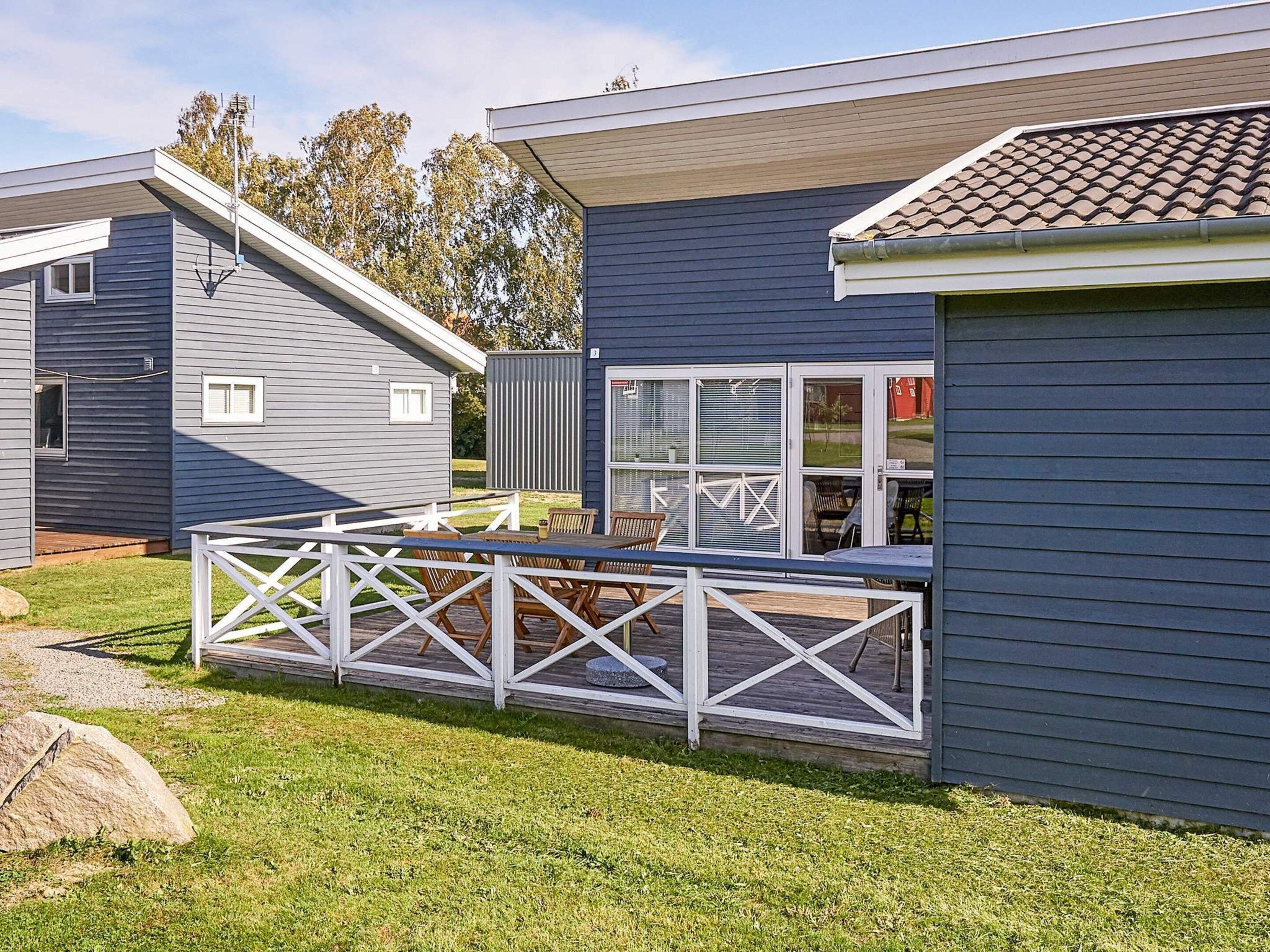 Imóvel residencial com área de pátio cercada, um pequeno deck e uma casa com telhado em cerâmica.