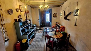 Um quarto aconchegante com uma mesa de jantar, cadeiras, um sofá e um candelabro.