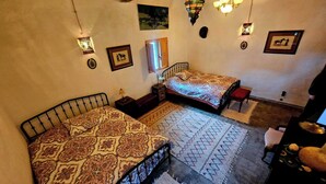 Quarto com duas camas, teto de madeira e um pequeno espaço de estar.