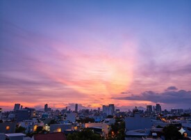 Paisagem urbana ao anoitecer com edifícios e um pôr do sol.