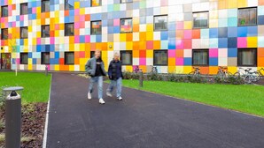 Um edifício com fachada em mosaico colorido e um calçada pavimentada.