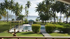 Uma área de piscina com um gazebo, espreguiçadeiras e vista para o oceano.