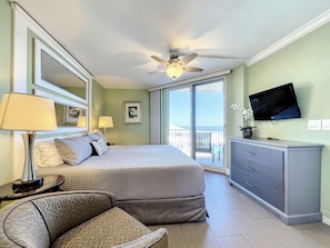 Quarto de hotel com cama, abajures, ventoinha no teto, televisão, cômoda e varanda com vista.