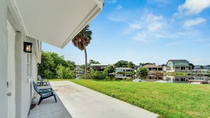 Um imóvel residencial com varanda coberta, área de estar externa e vista para casas vizinhas e um corpo d'água.