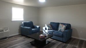 Uma sala de estar com dois sofás azuis, uma mesa de centro e uma janela.