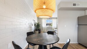 Uma cozinha moderna com uma mesa de jantar redonda, cadeiras pretas e um pendente amarelo.