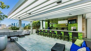 Uma área externa com espaço para sentar, incluindo bar, sofás e cadeiras.