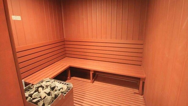 Uma sauna com bancos de madeira e um elemento de aquecimento de pedra.