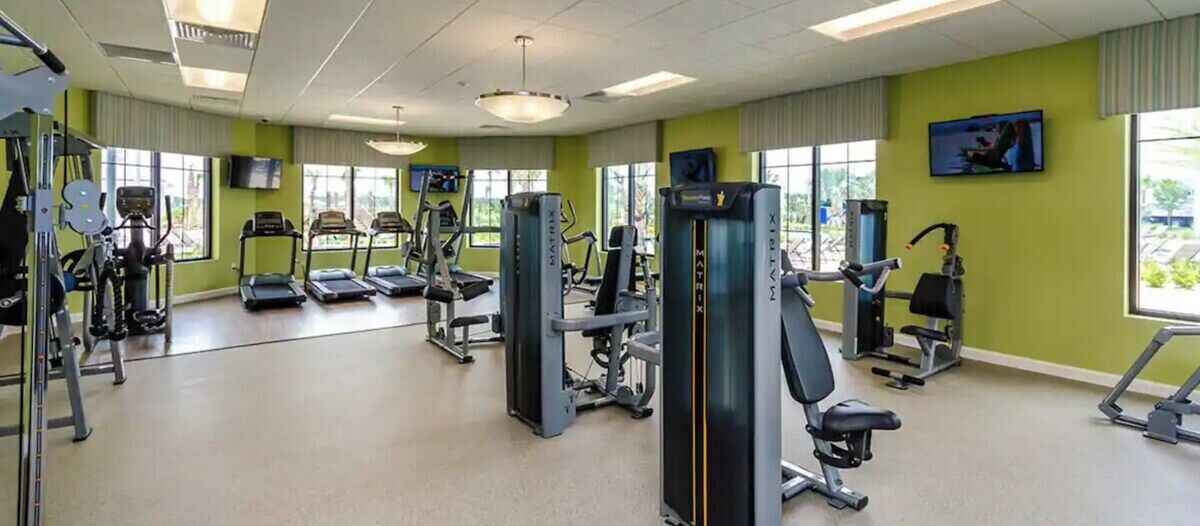 Academia com esteiras, máquinas de peso e bolas de exercício.