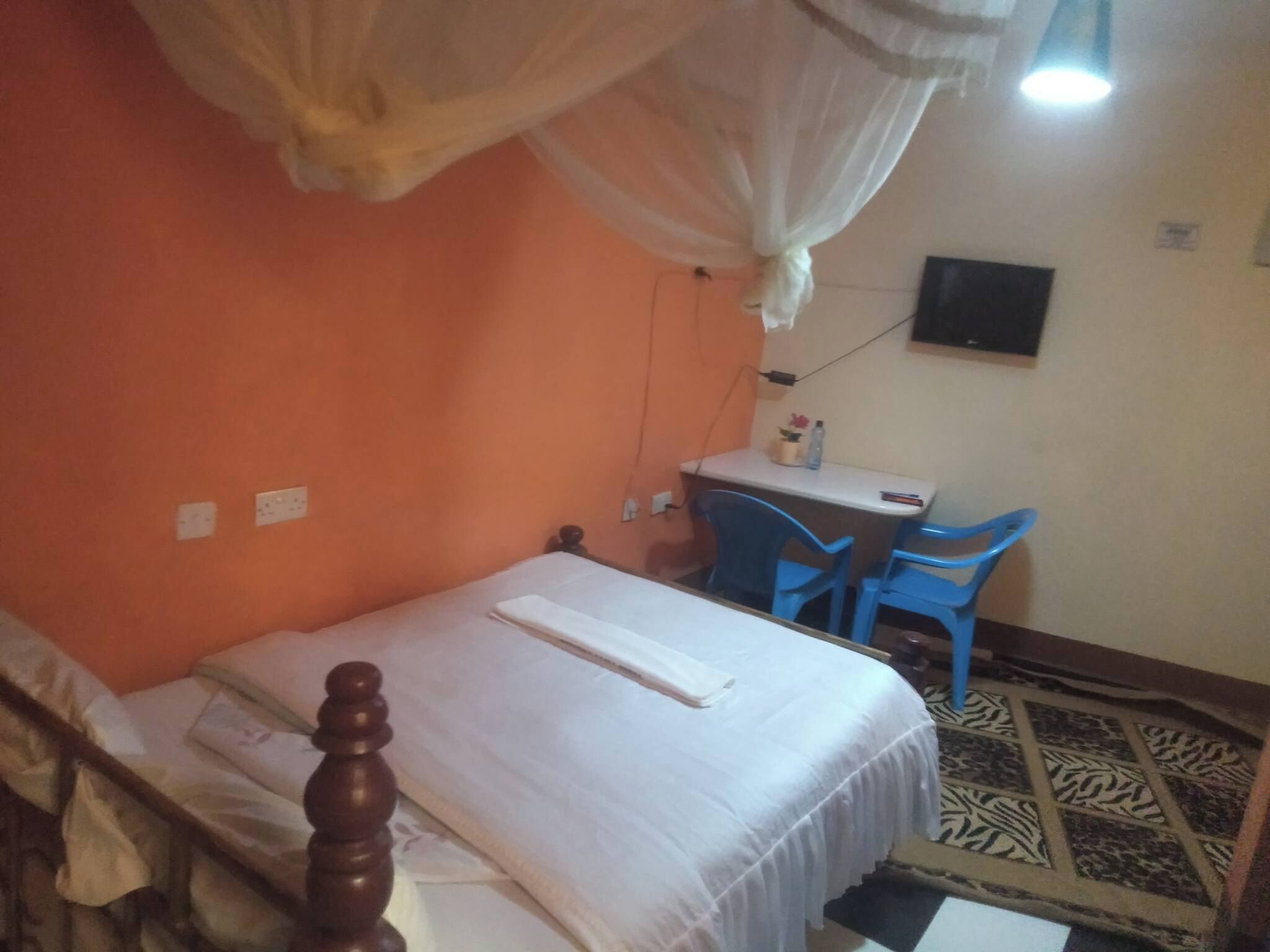 Quarto com uma cama, uma escrivaninha e duas cadeiras.