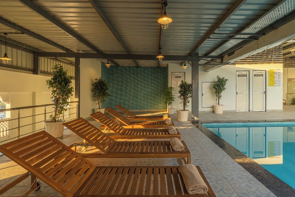 Uma área à beira da piscina com espreguiçadeiras e plantas em vasos.