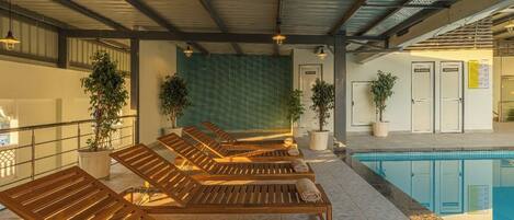 Uma área à beira da piscina com espreguiçadeiras e plantas em vasos.