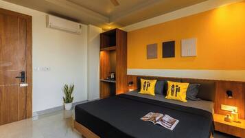 Quarto de hotel moderno com uma cama grande, cabeceira de madeira e uma parede de destaque em amarelo vibrante.