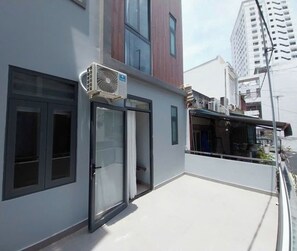 Um edifício moderno com entrada por porta de vidro, unidade de ar condicionado e varanda.