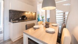 Uma cozinha moderna com cafeteira embutida, uma mesa de jantar com cadeiras e uma luminária pendente.