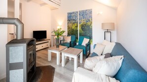 Uma sala de estar moderna com televisão, sofá, cadeiras, mesa e lareira.
