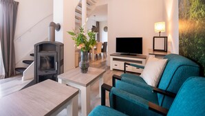 Uma sala de estar moderna com lareira, televisão de tela plana, sofá e área de jantar.