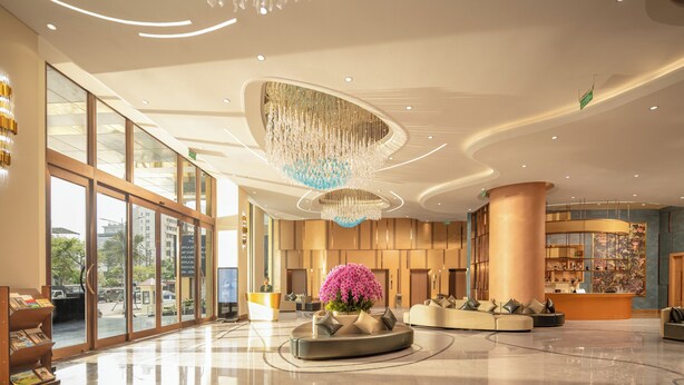 Um hall amplo com um grande candelabro, uma mesa de recepção e uma área de estar.