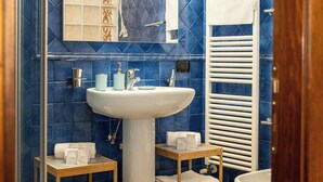 Um banheiro com pia branca, azulejos azuis nas paredes, um espelho e um porta-toalhas.