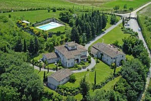 Uma propriedade extensa com três edifícios principais, uma piscina e jardins bem cuidados.