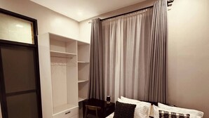 Um quarto com uma cama, um guarda-roupa, uma escrivaninha e uma cadeira.