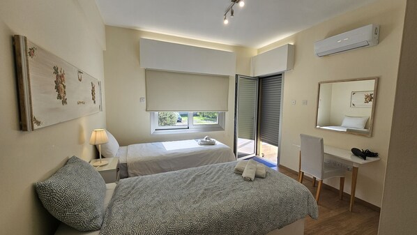Quarto com cama, mesas de cabeceira, escrivaninha, cadeira, janela e espelho.