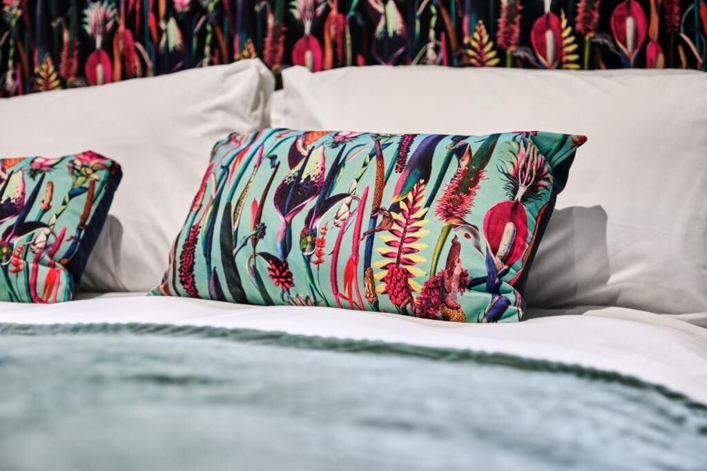 Cama com duas almofadas coloridas estampadas com flores.