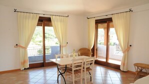 Um quarto com mesa de jantar e cadeiras, um sofá e uma janela com cortinas.