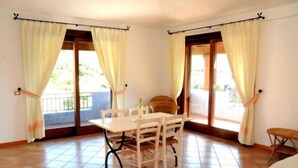Um quarto com uma mesa de jantar e cadeiras, um sofá e uma janela com cortinas.