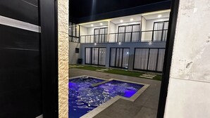 Um edifício moderno com piscina, varanda coberta e fachada bem iluminada.