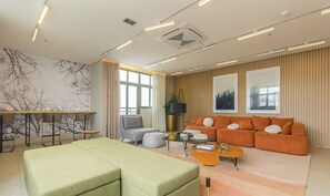 Uma sala de estar moderna com um sofá verde, um sofá laranja e uma poltrona cinza. Há uma mesa de jantar com cadeiras e uma grande janela com cortinas.