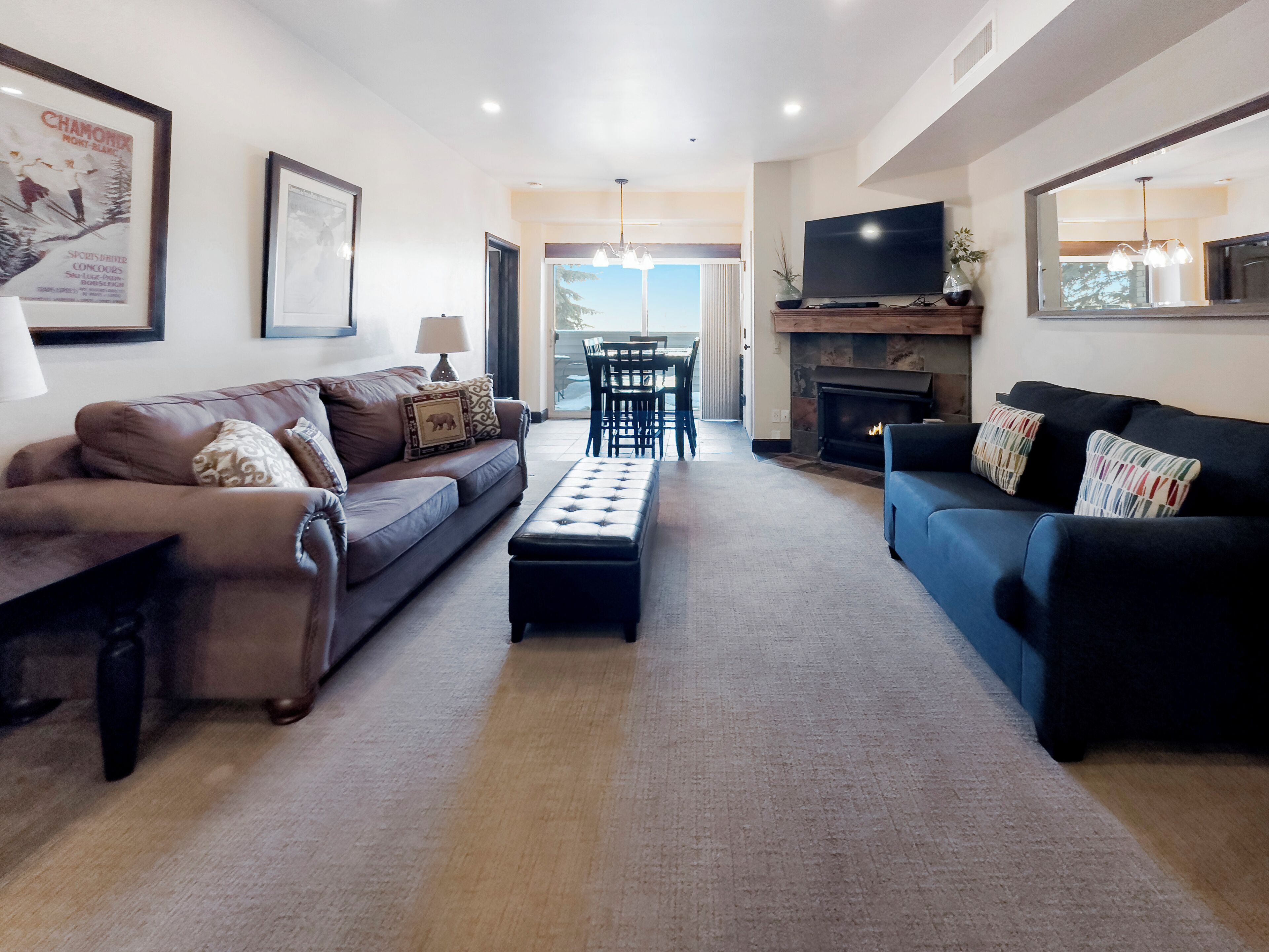 Uma sala de estar moderna com lareira, televisão e um espaço de jantar com cadeiras.