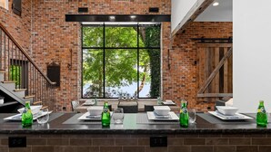 Restaurante com parede de tijolos e grandes janelas com vista para o verde.