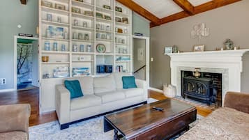 Uma sala de estar com sofá branco, mesa de centro e lareira.