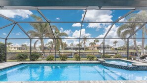 Piscina com vista para palmeiras e casas ao fundo.