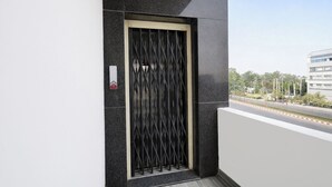 Edifício moderno com portão de metal preto e uma pequena janela.