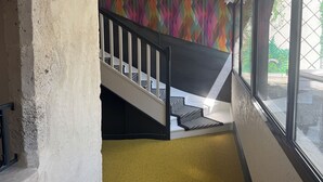 Uma escadaria com parede estampada, janela com vista para vegetação e parede texturizada.