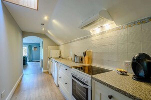 Uma cozinha moderna com armários brancos, forno embutido e bancada de granito.