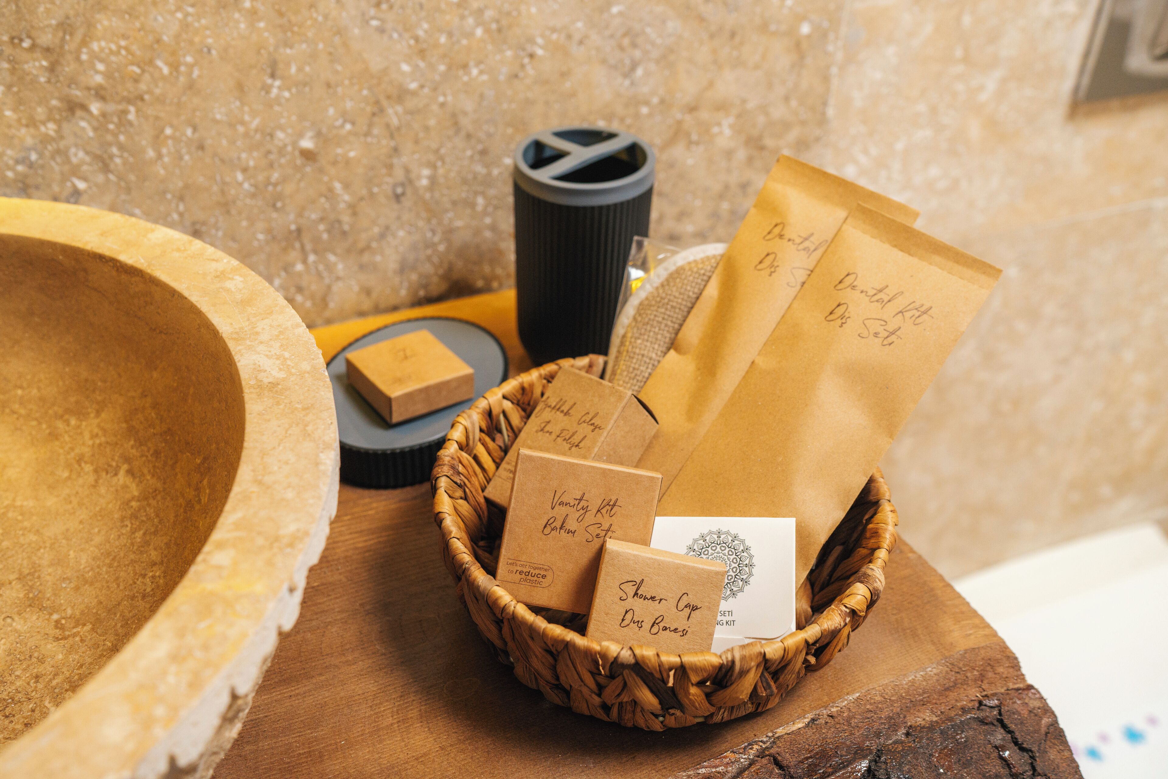 Uma bacia de madeira, uma cesta de vime com sacolas de presente e uma lixeira preta.