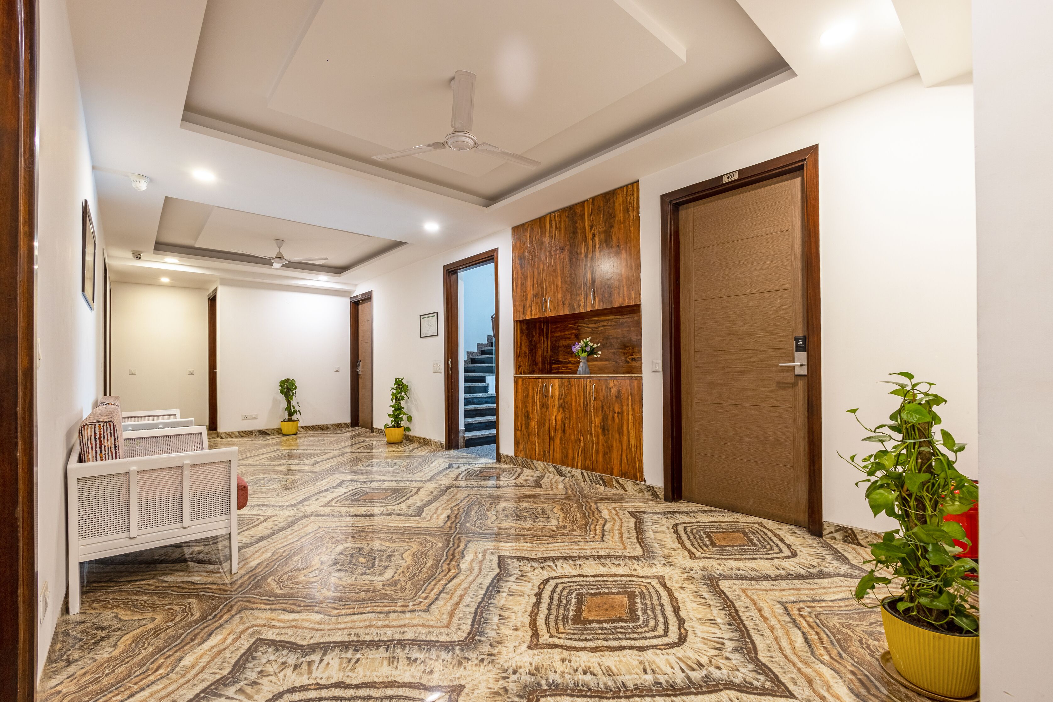 Um corredor com piso estampado, uma mesa de recepção, uma escada e uma área de atendimento.