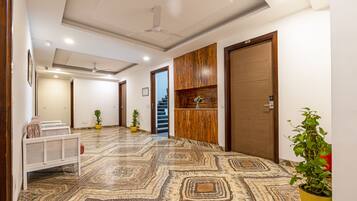 Um corredor com piso estampado, uma mesa de recepção, uma escada e uma área de atendimento.