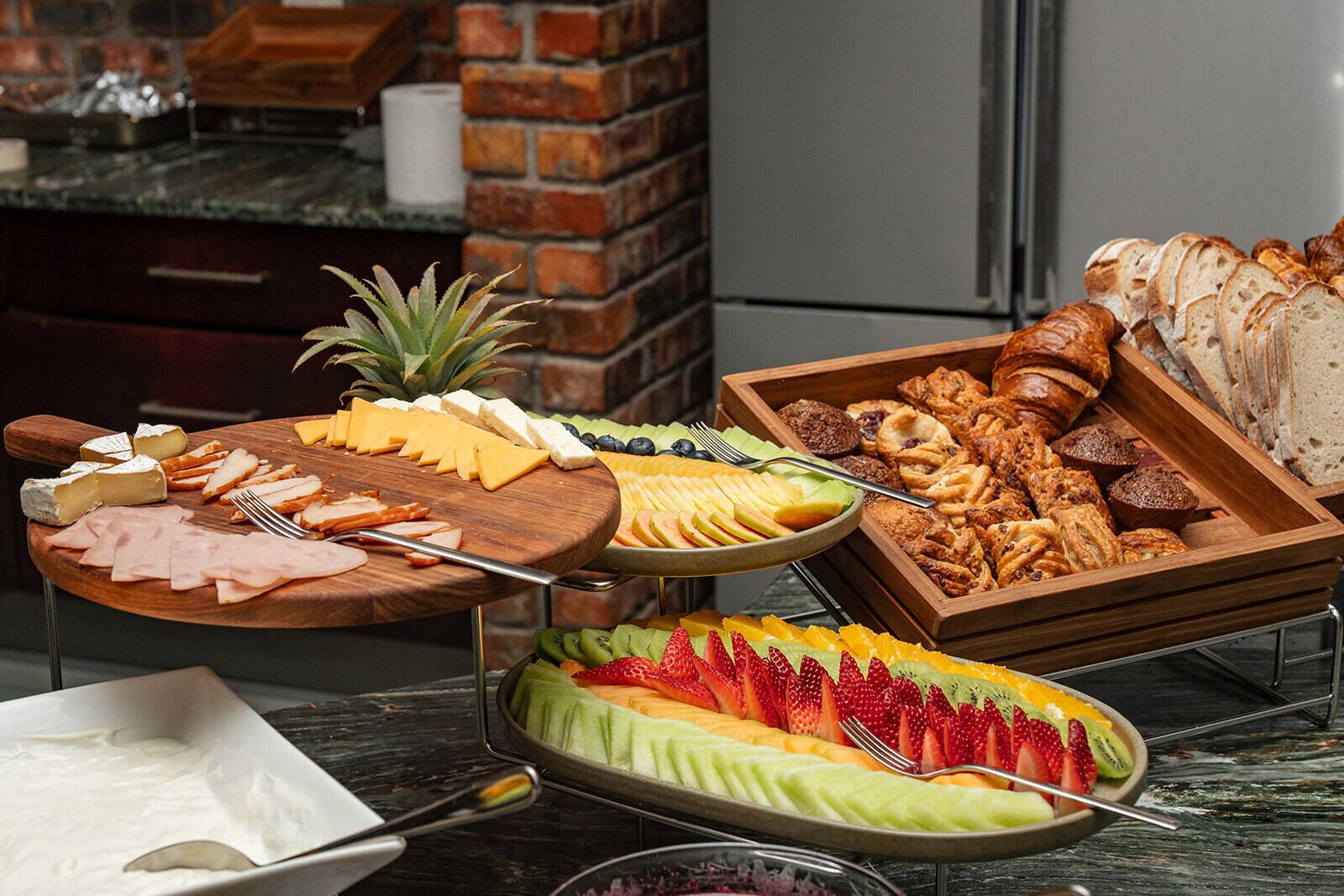 Buffet com diversos alimentos, incluindo queijos, frutas e doces.