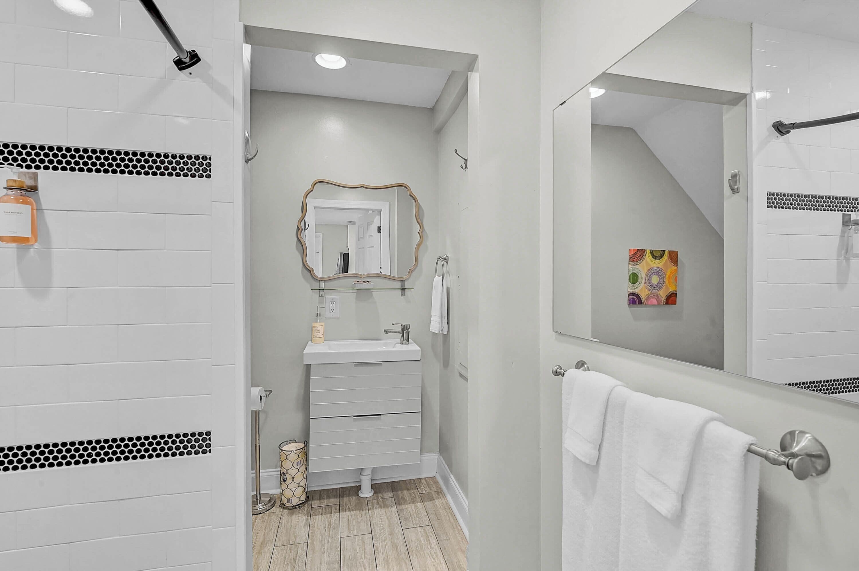 Uma casa de banho moderna com uma pia branca, um espelho e uma área de duche.