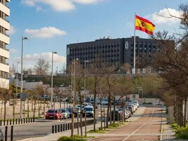Um estacionamento com carros, uma bandeira e um edifício ao fundo.