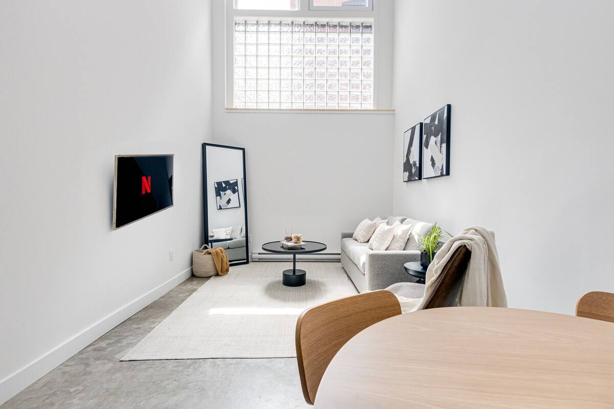 Uma sala de estar moderna com sofá, mesa de centro e televisão fixada na parede.