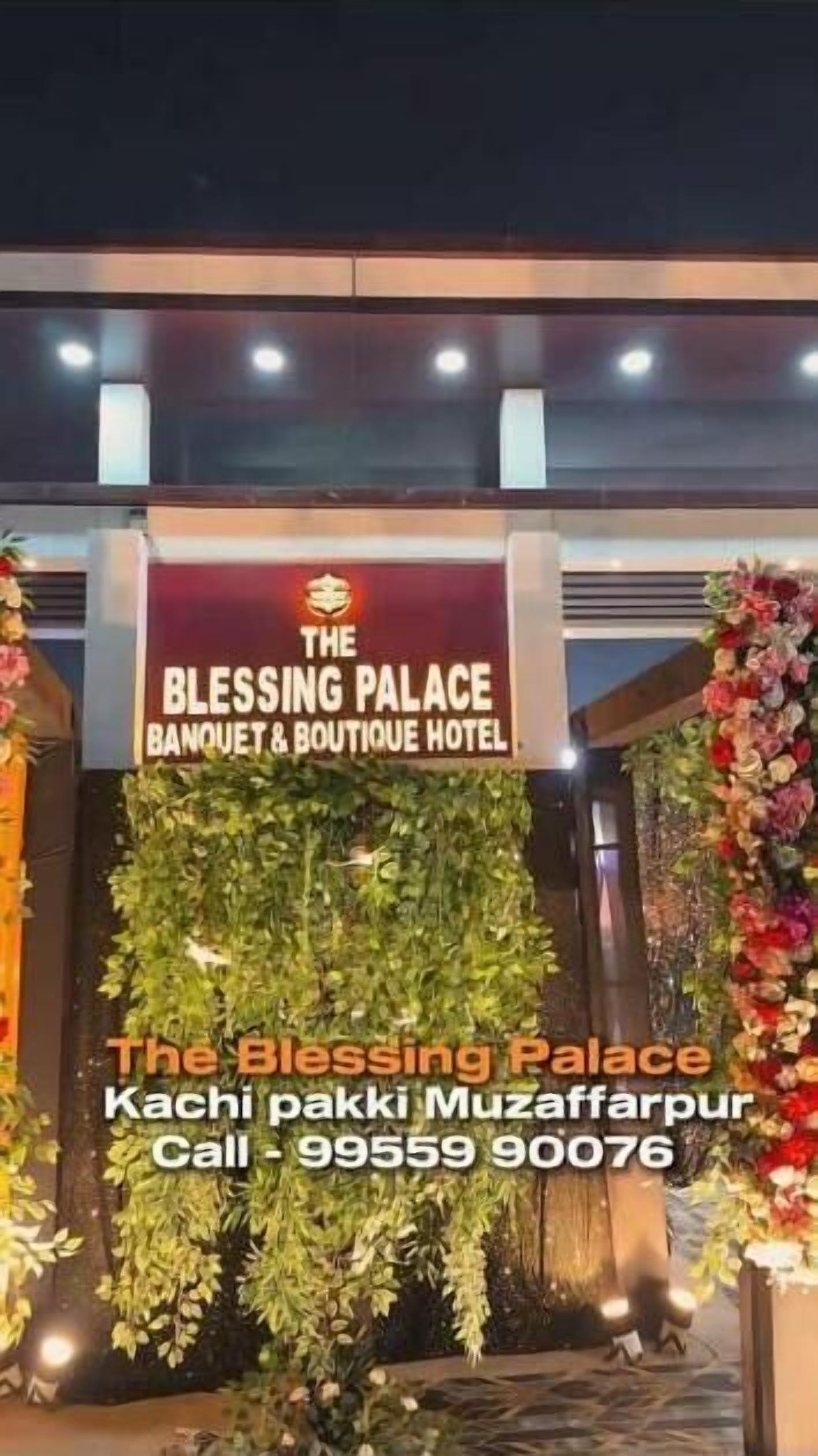 A entrada do The Blessing Palace Banquet & Boutique Hotel, com uma placa e plantas decorativas.