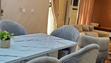 Uma sala de jantar com mesa de mármore, cadeiras estofadas e um ar condicionado moderno.