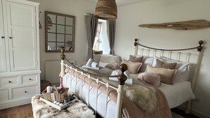 Quarto com cama, guarda-roupa, espelho e luminária suspensa.